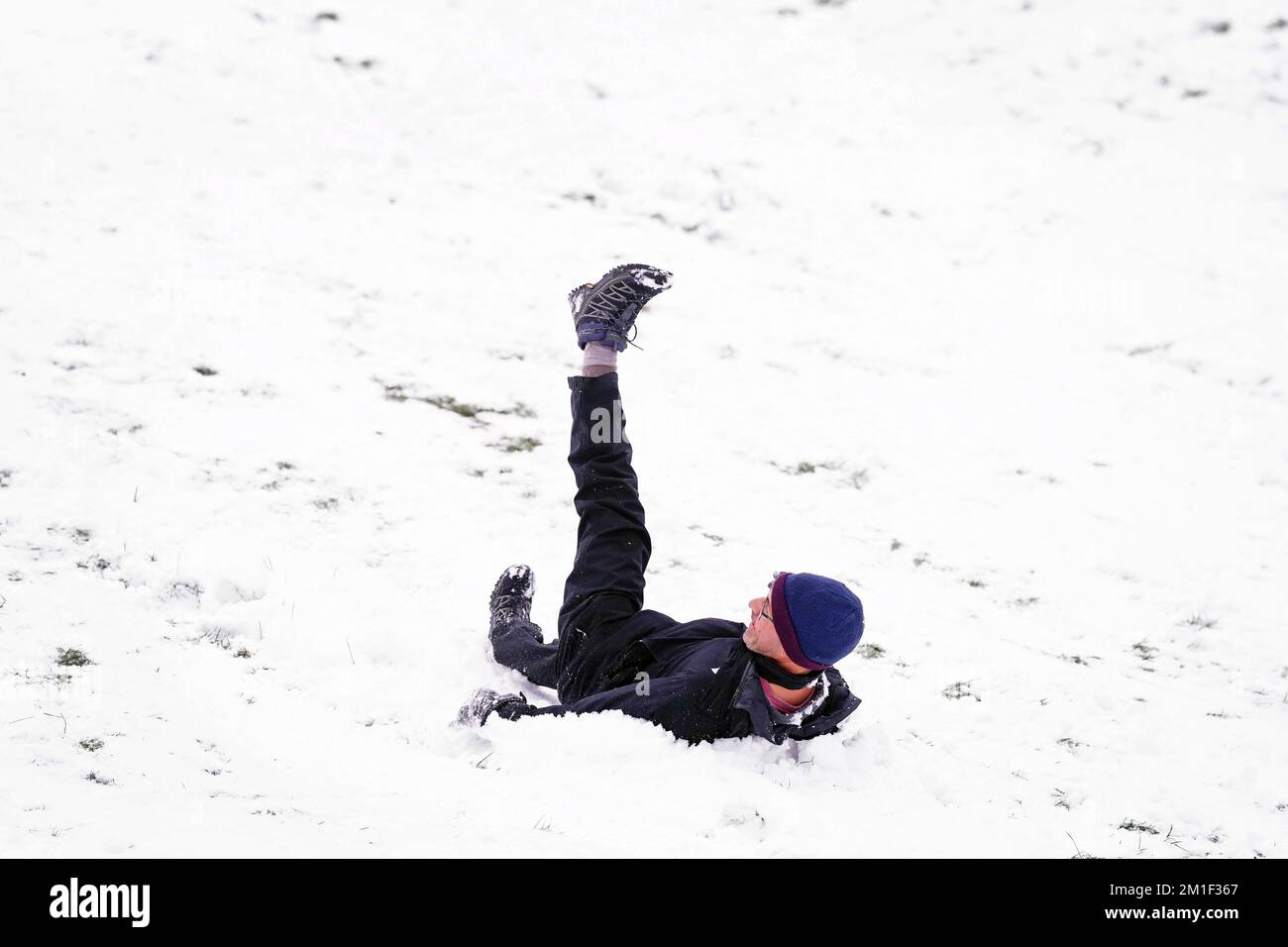 A man falls over in the snow in Greenwich Park, south-east London. Snow ...