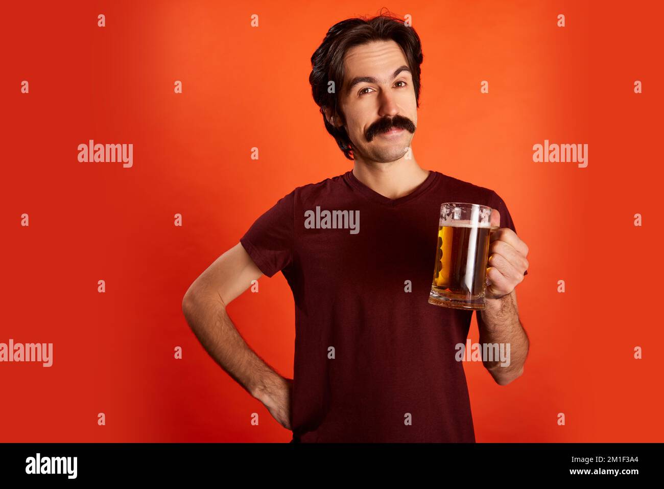 Portrait of man with moustache smiling, posing with lager beer mug ...