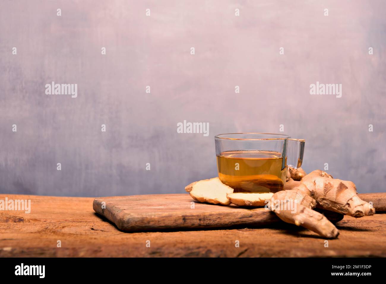 Hot ginger-infused cup on a white table with sliced ginger root in a ...