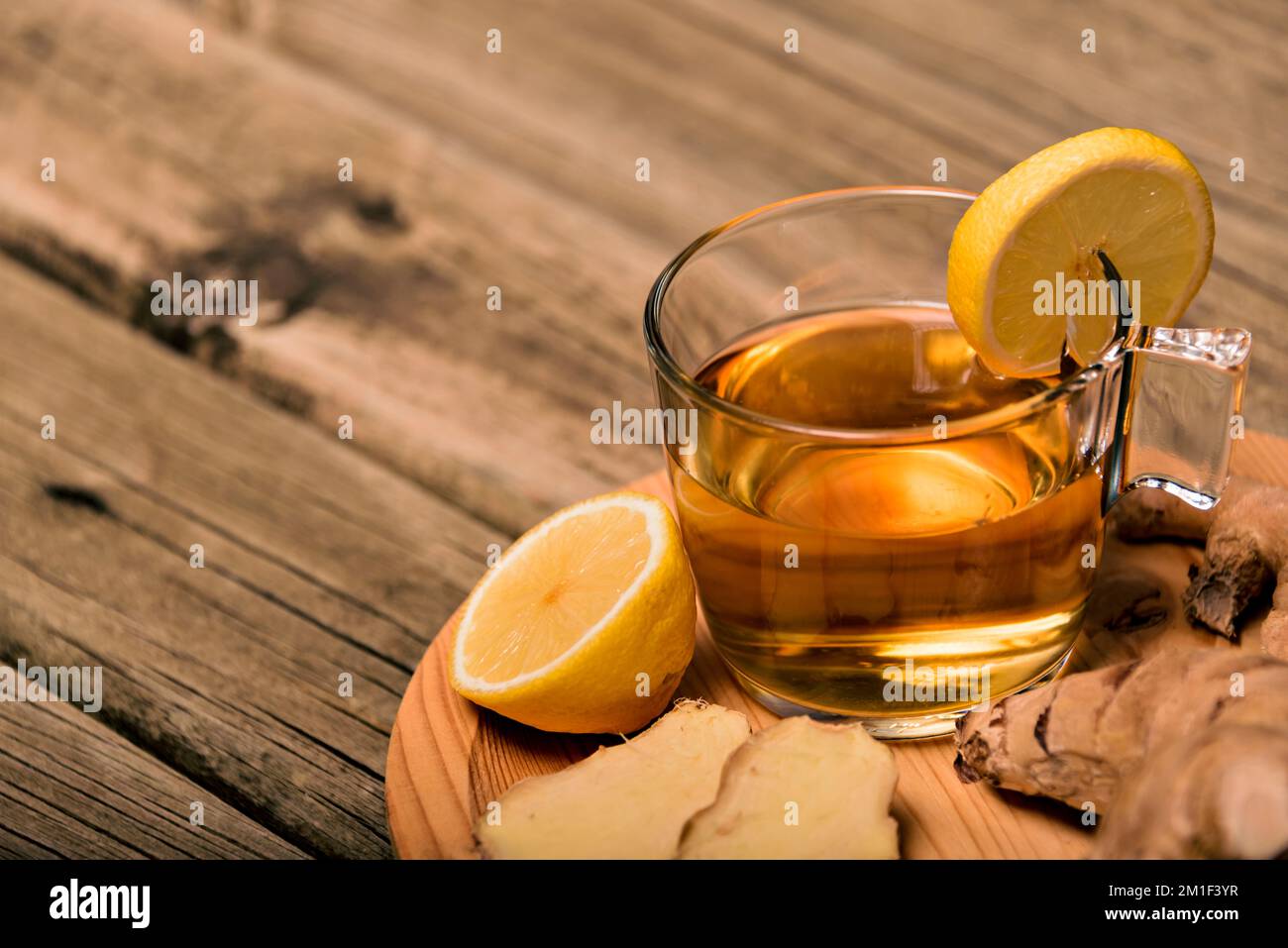 Hot ginger-infused cup on a white table with sliced ginger root in a ...