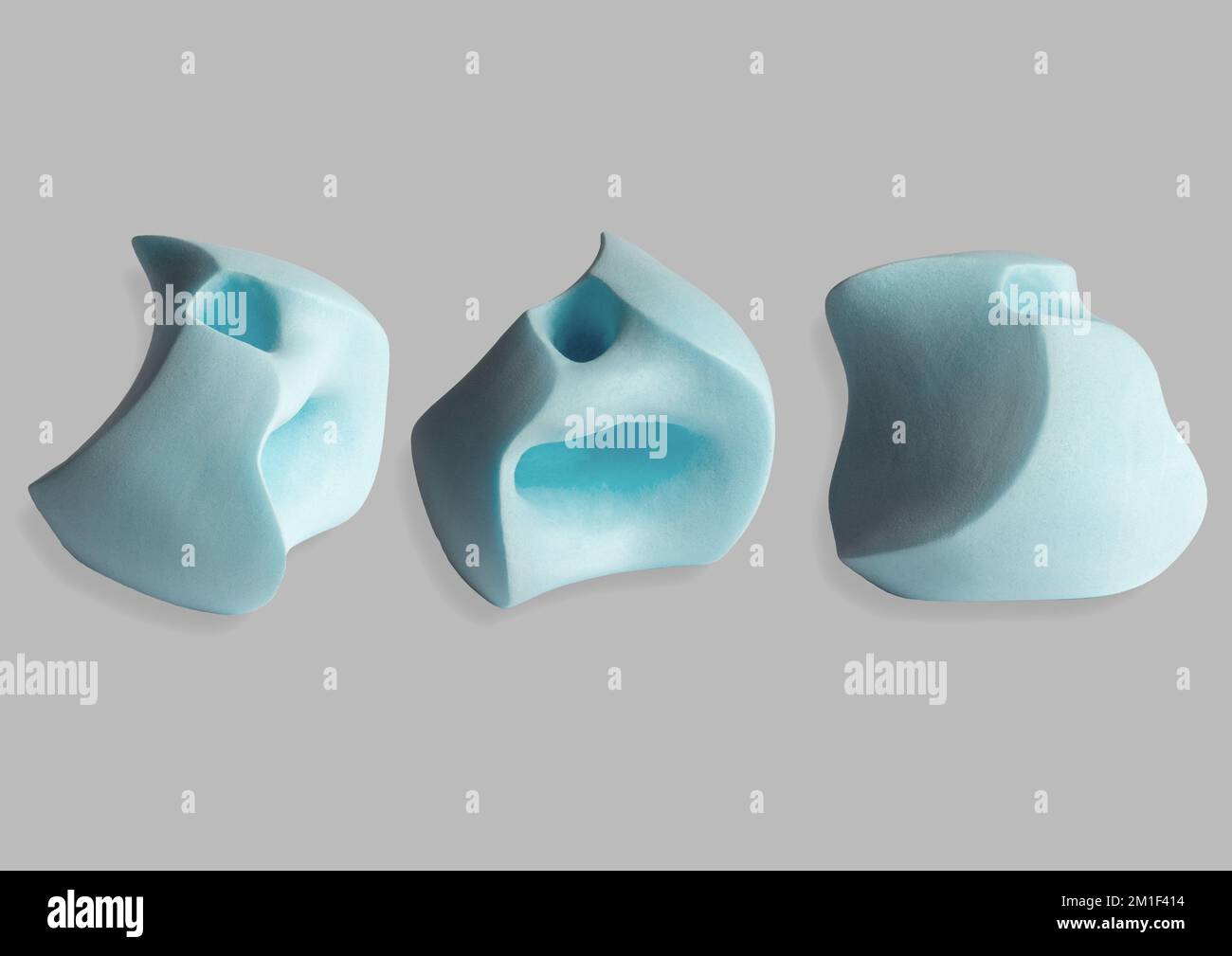 Three blue abstract objects floating in the air on a light gray ...