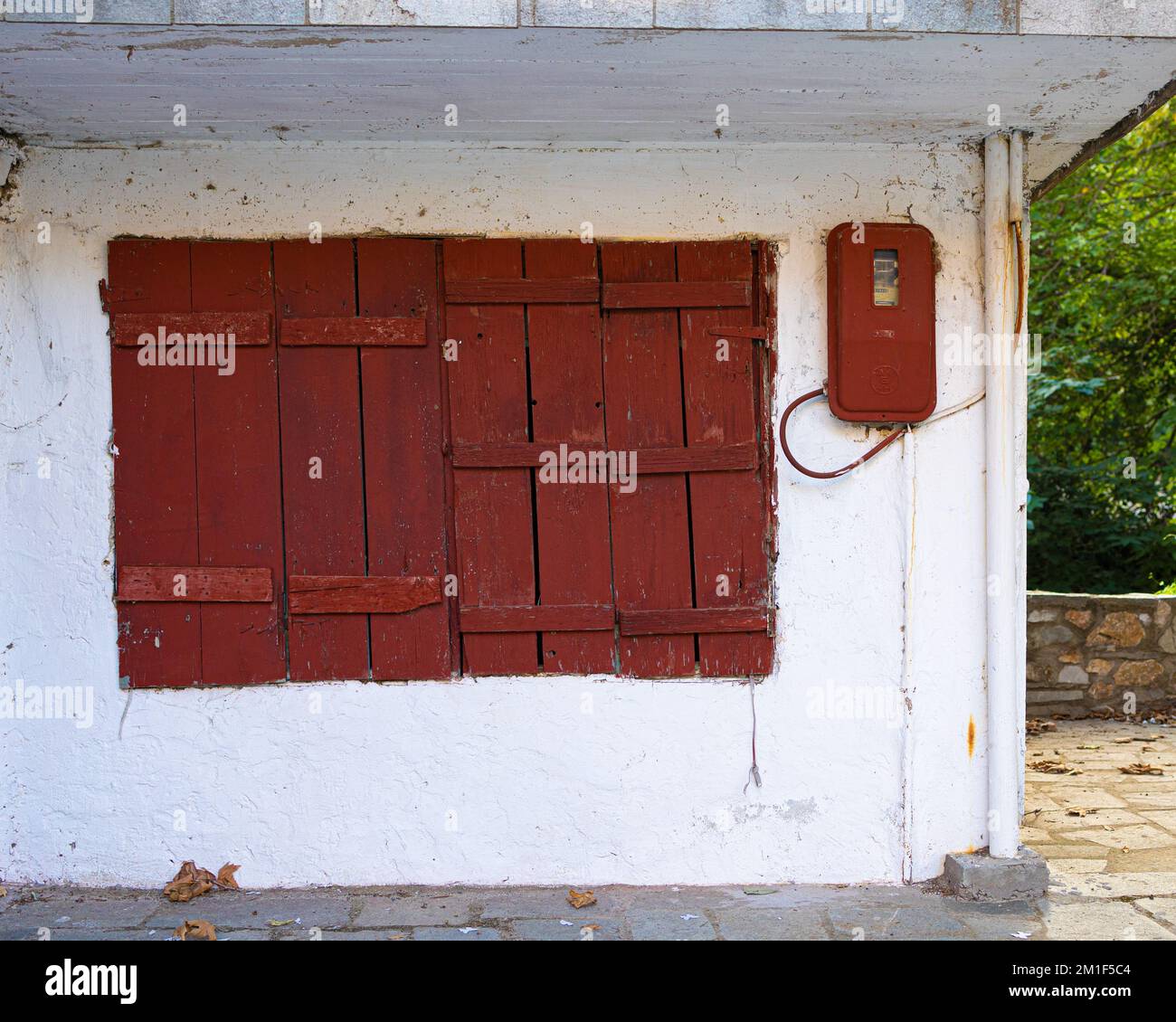 A wooden red window and an electric meter box on an old white wall ...