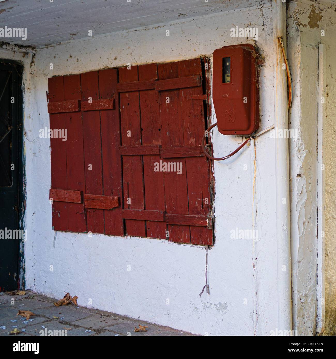 A wooden red window and an electric meter box on an old white wall ...