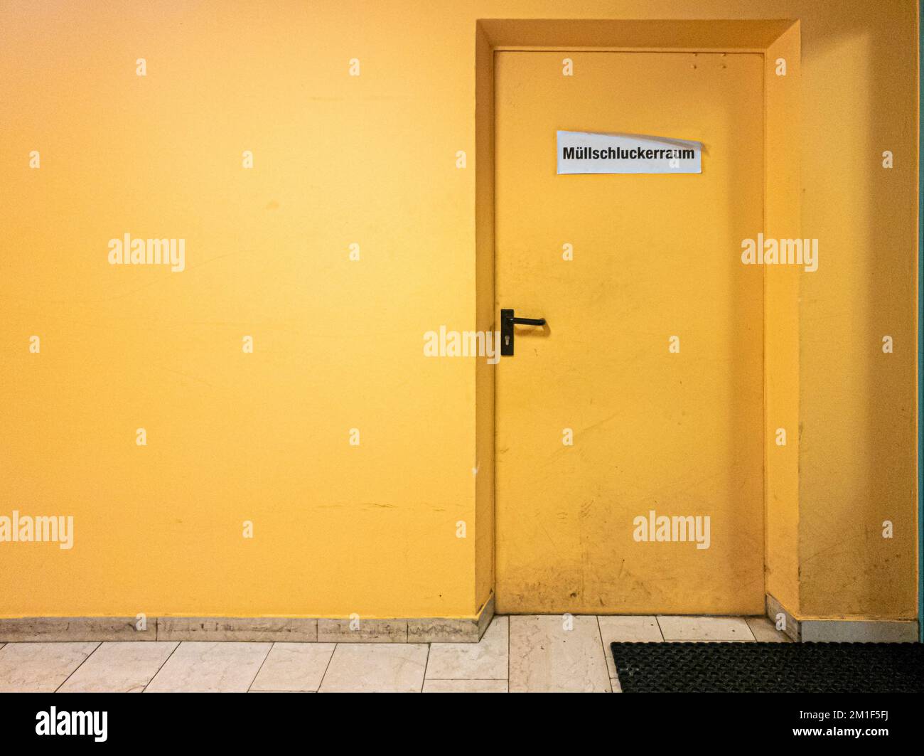 A yellow door on a yellow wall with a garbage chute room sign on it ...