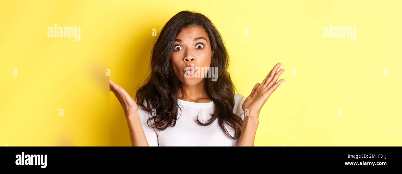Close-up of surprised african-american girl, raising hands up and ...