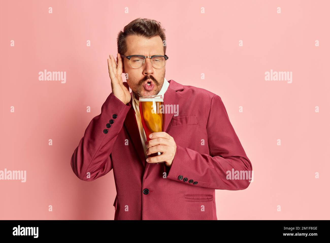 Portrait of stylish drunk man in a suit posing with glass of lager beer ...