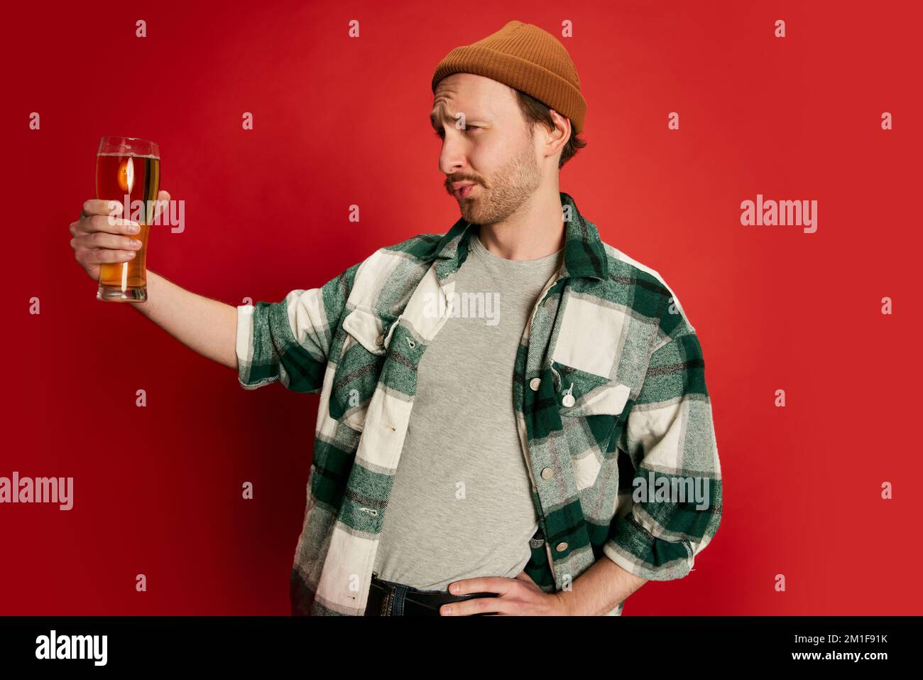 Portrait of young man in casual checkered shirt posing with beer ...