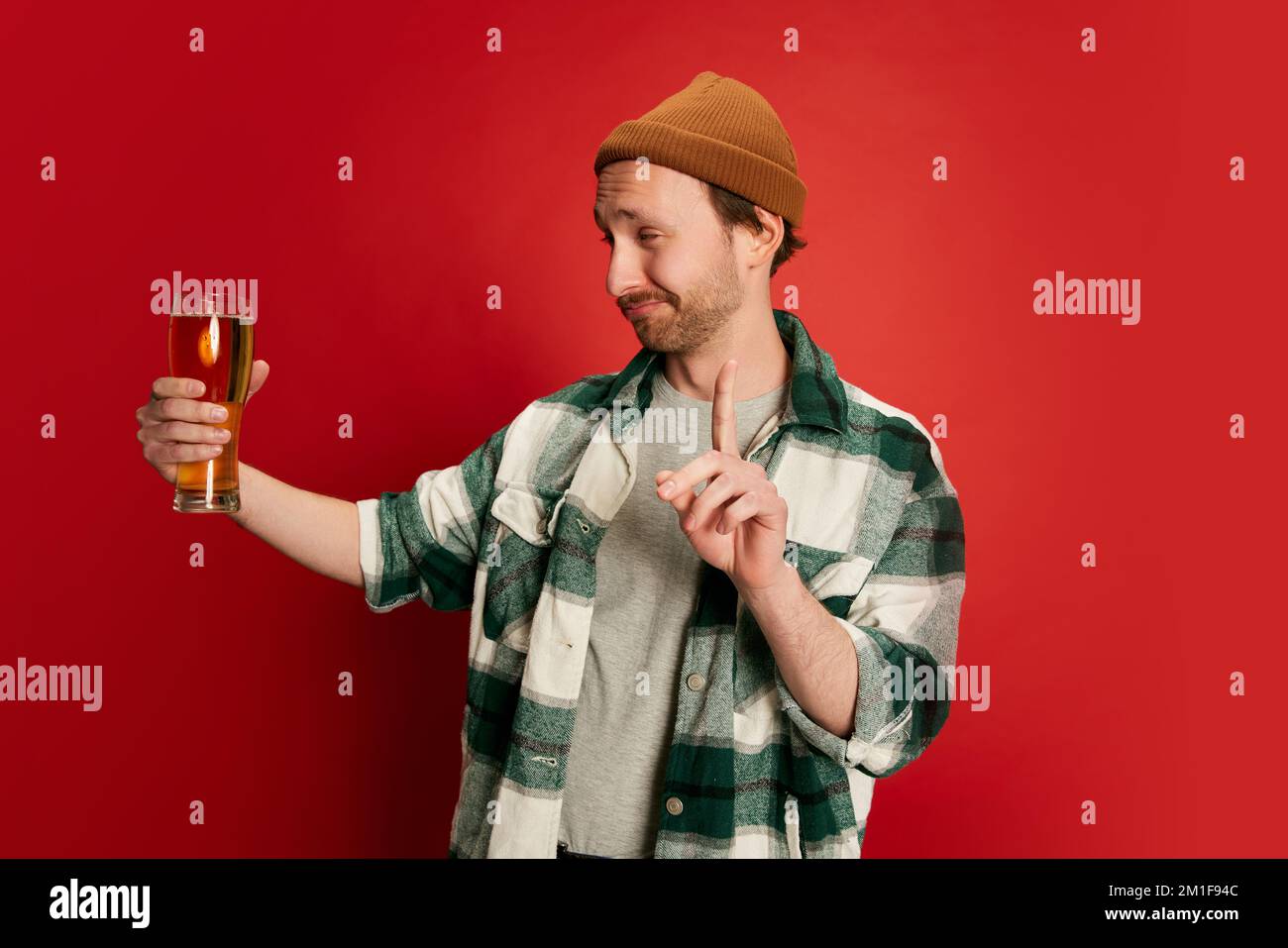 Portrait of young man in casual checkered shirt posing with beer ...