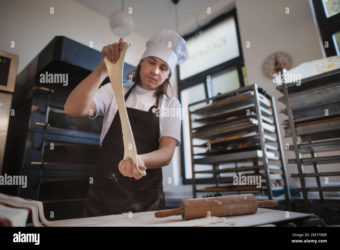 Young baker with chef cap preparing pastries in bakery Stock Photo - Alamy