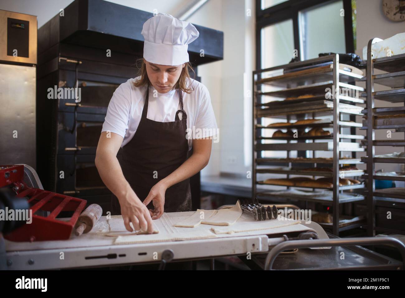 Young baker with chef cap preparing pastries in bakery Stock Photo - Alamy
