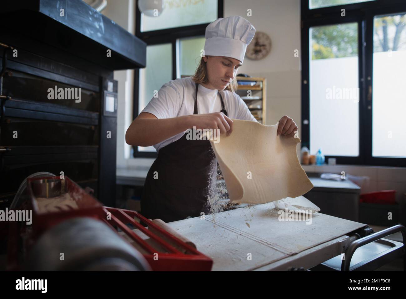 Young baker with chef cap preparing pastries in bakery Stock Photo - Alamy