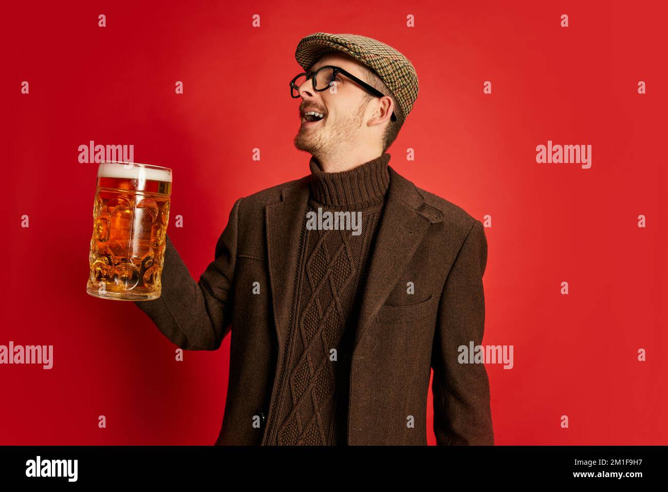 Portrait of stylish man in classical clothes posing with glass of foamy ...