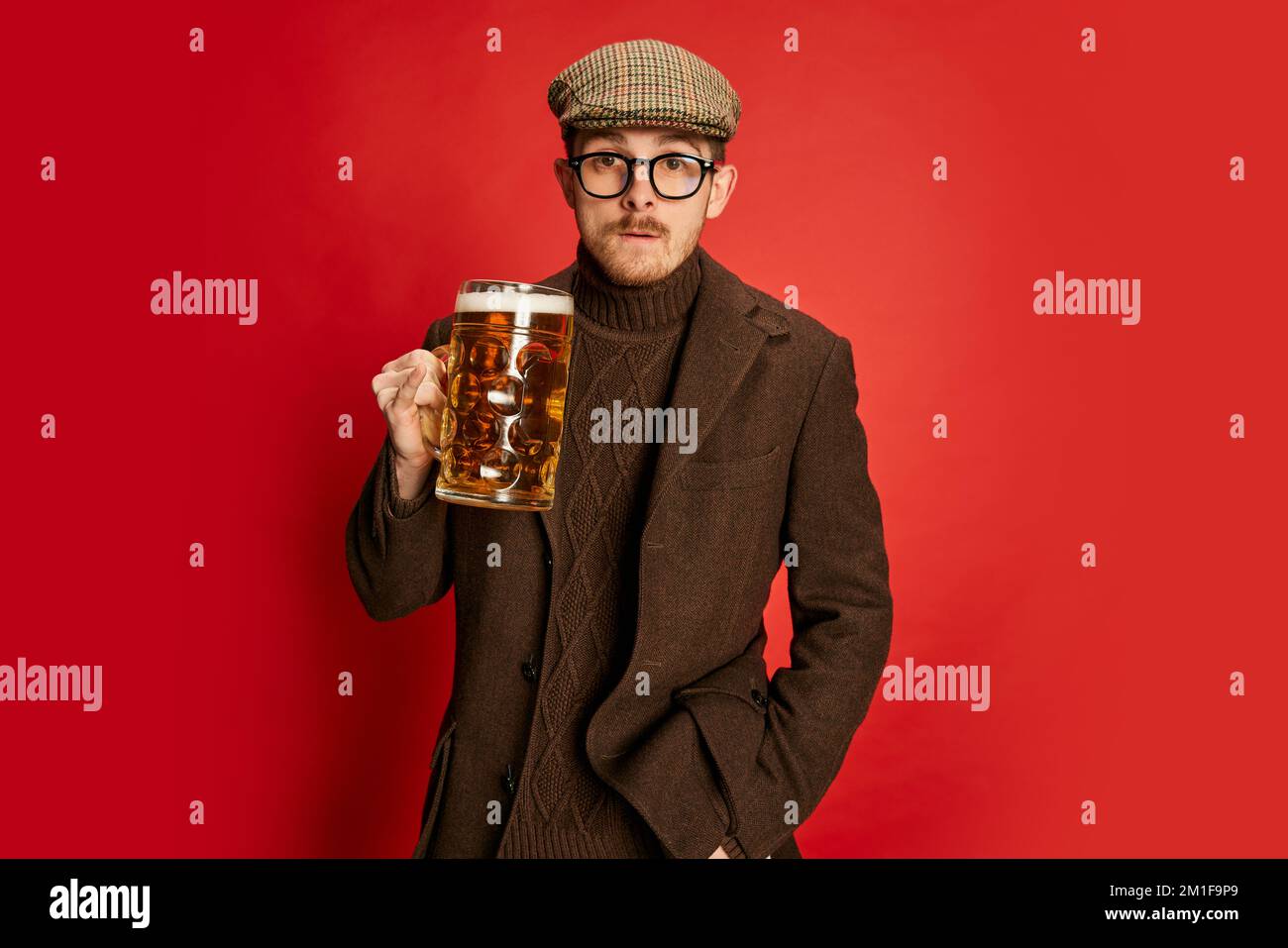 Portrait of stylish man in classical clothes posing with glass of foamy ...