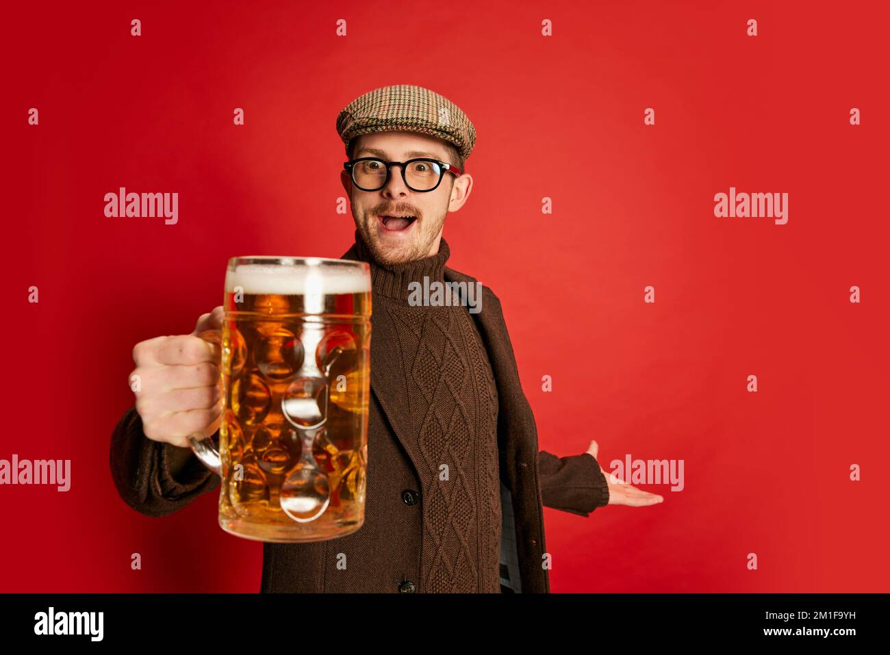 Portrait of stylish man in classical clothes posing with glass of foamy ...