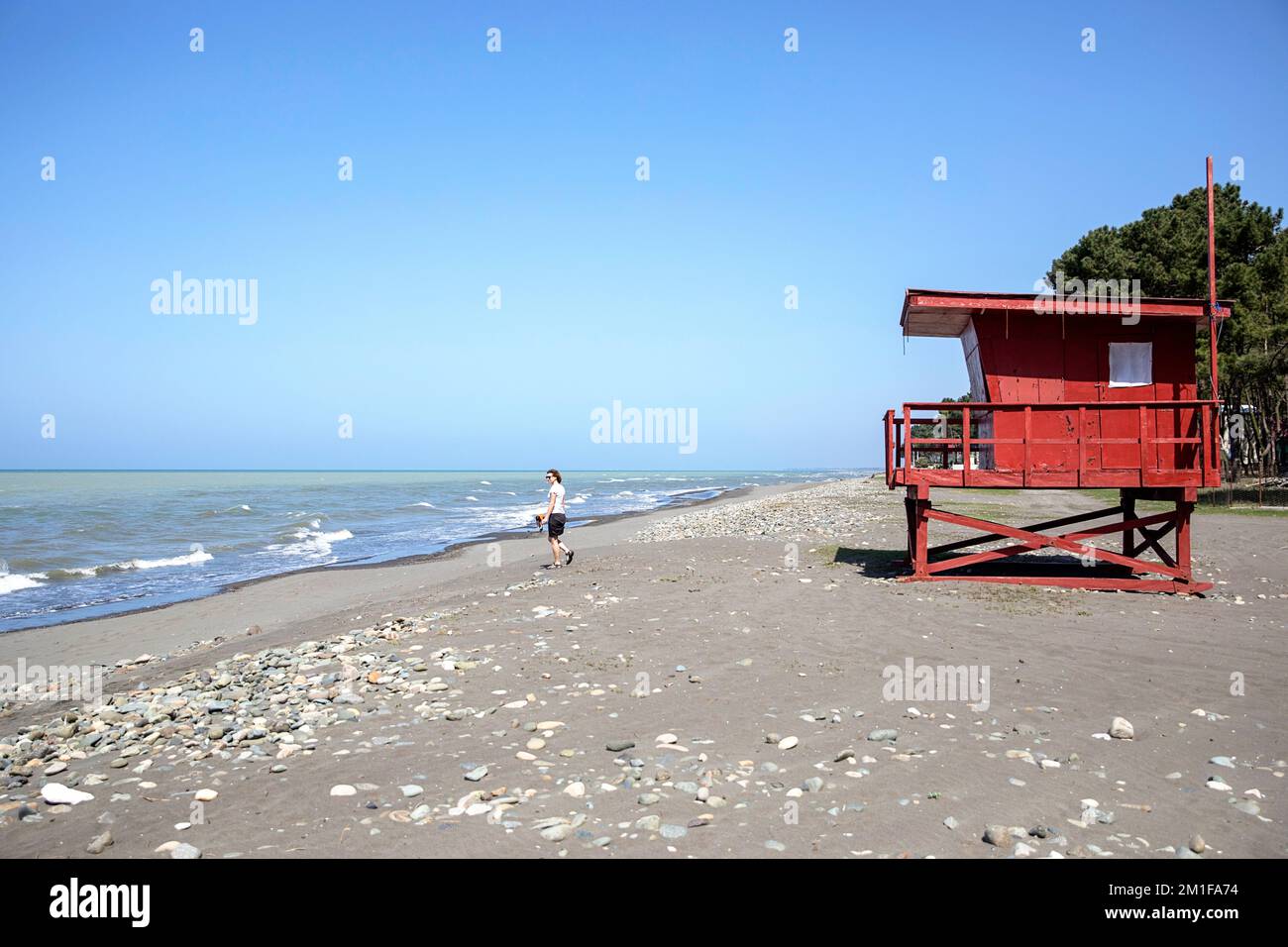 Woman walking on the Shekvetili Beach with iconic lifeguard tower on ...