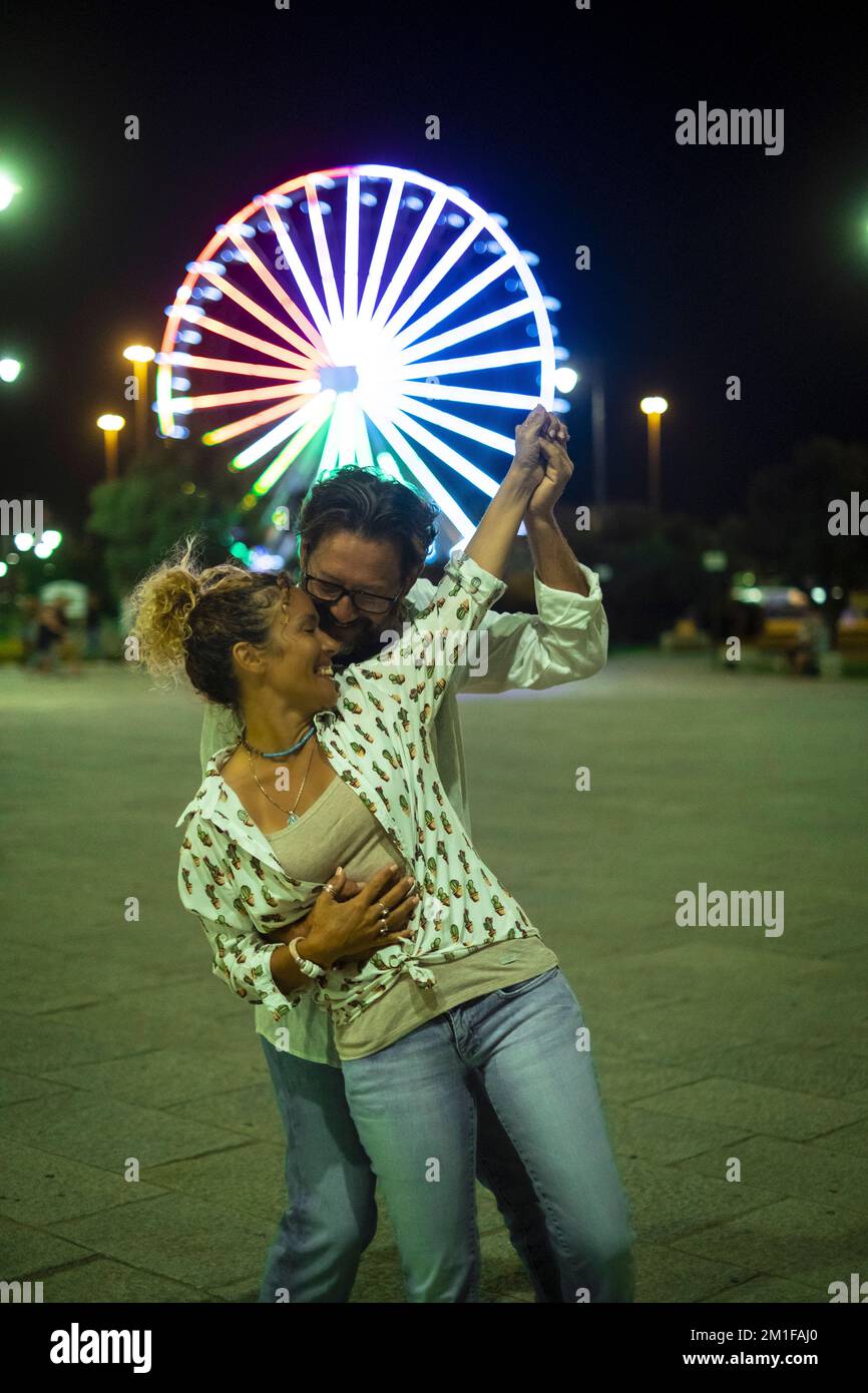 Mature youth couple dance outdoor with luna park attractions in ...