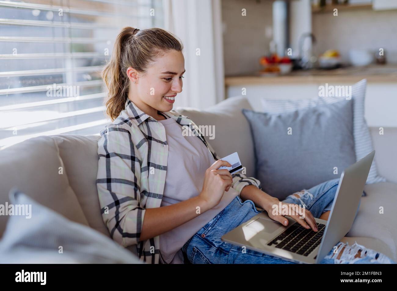 Young woman resting on sofa and shopping online with her credit card ...