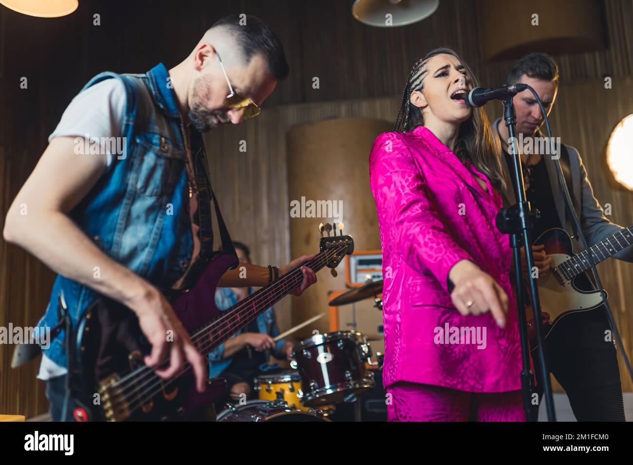 a singer woman in pink clothes standing in front of guitarists and a ...