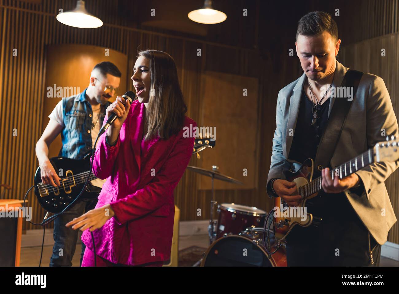 music band rehearsal in the reconding studio, guitarists, a singer and ...