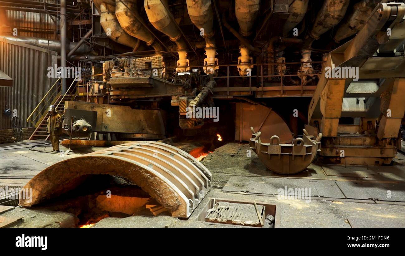 Steelworkers standing near a blast furnace with sparks at the ...