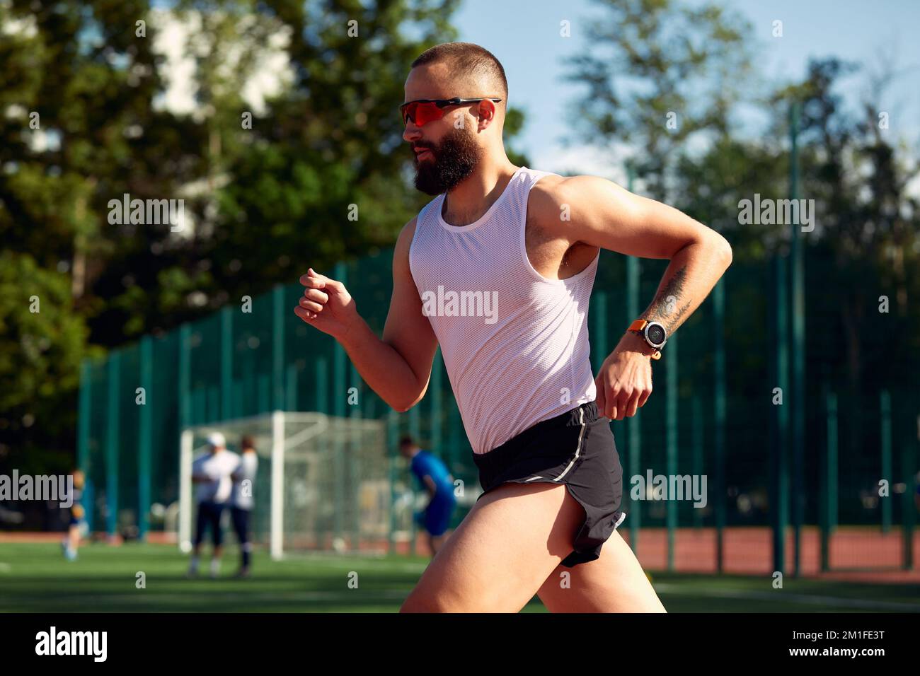 Side view of a male athlete sprinting on a running track in a track and ...