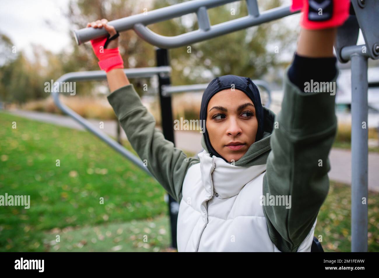 Young muslim woman in sports hijab doing work out in outdoor training ...