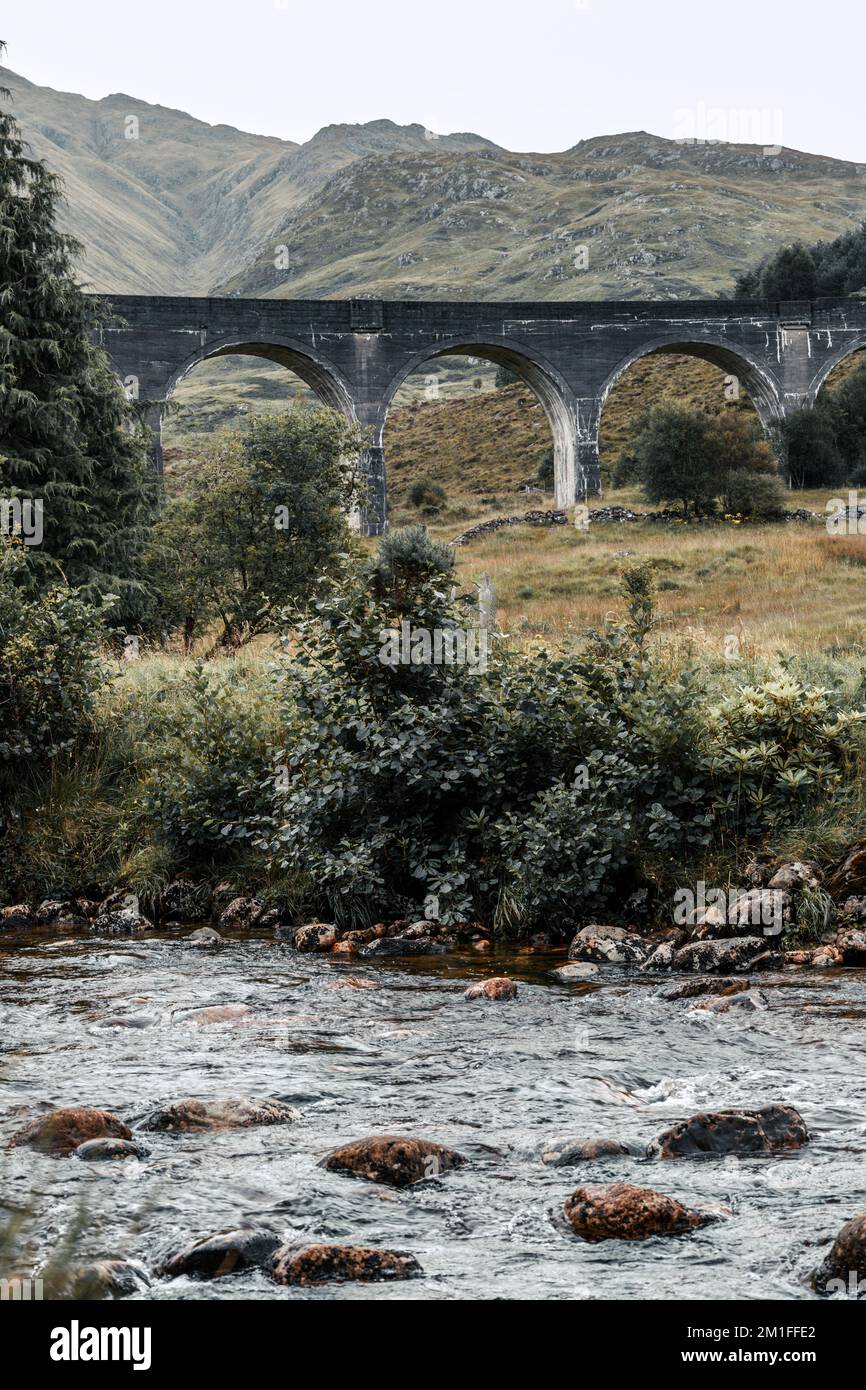 A vertical shot of a historic arched bridge over the Glenfinnan Viaduct ...