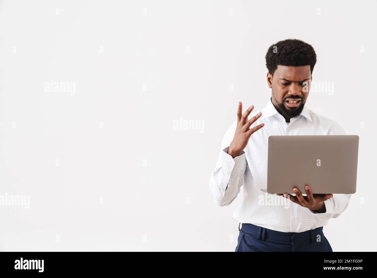 Black displeased man gesturing while working with laptop isolated over ...