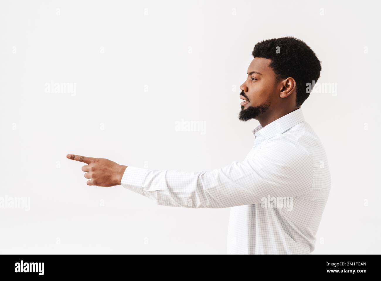 Black mid man wearing shirt looking and pointing finger aside isolated ...