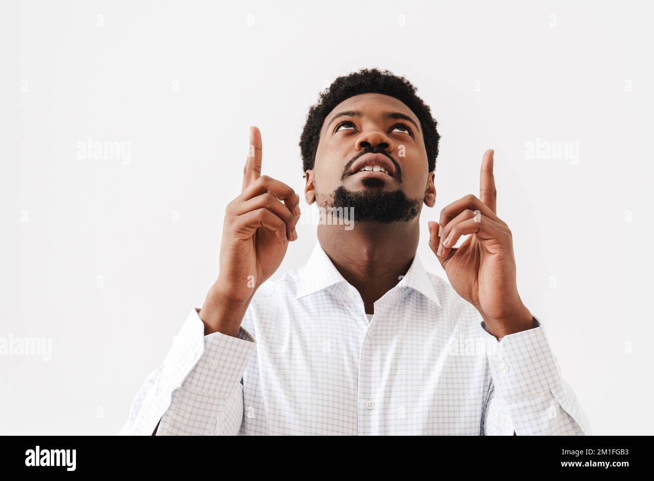 Black mid man wearing shirt looking and pointing finger upward isolated ...