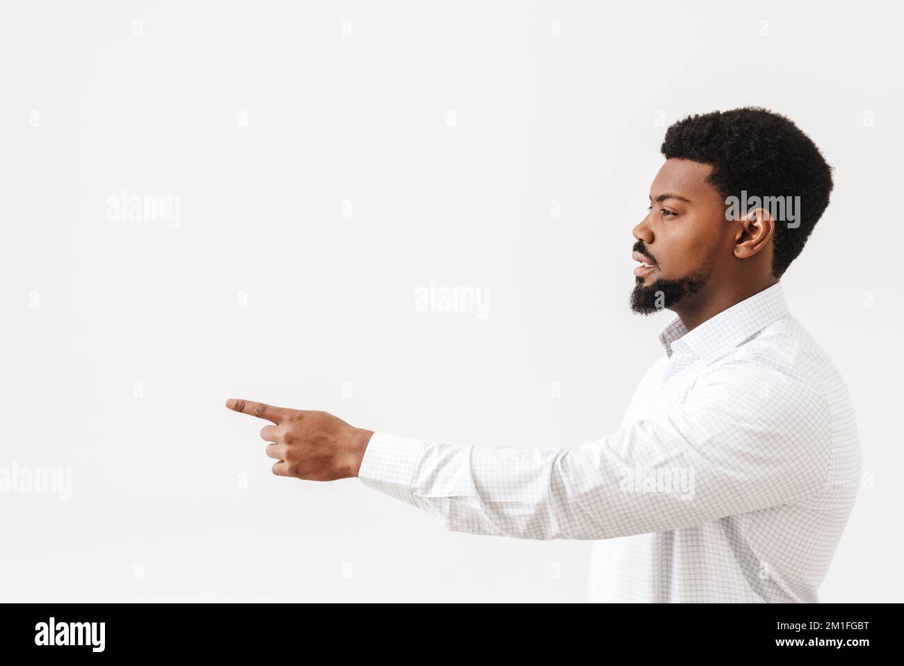 Black mid man wearing shirt looking and pointing finger aside isolated ...