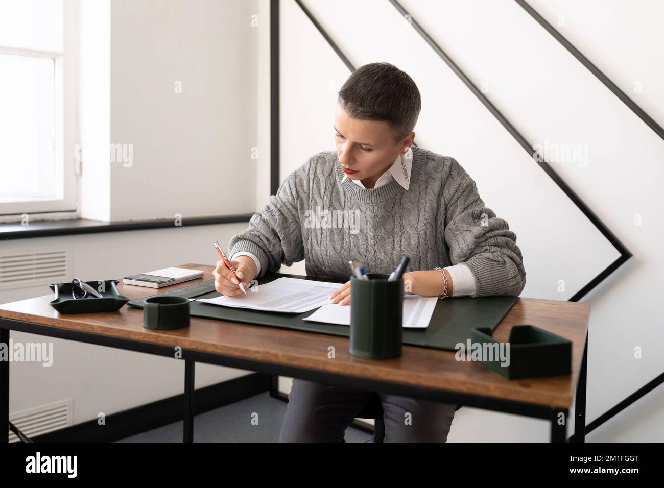 woman signs documents sitting on the desktop in the office Stock Photo ...