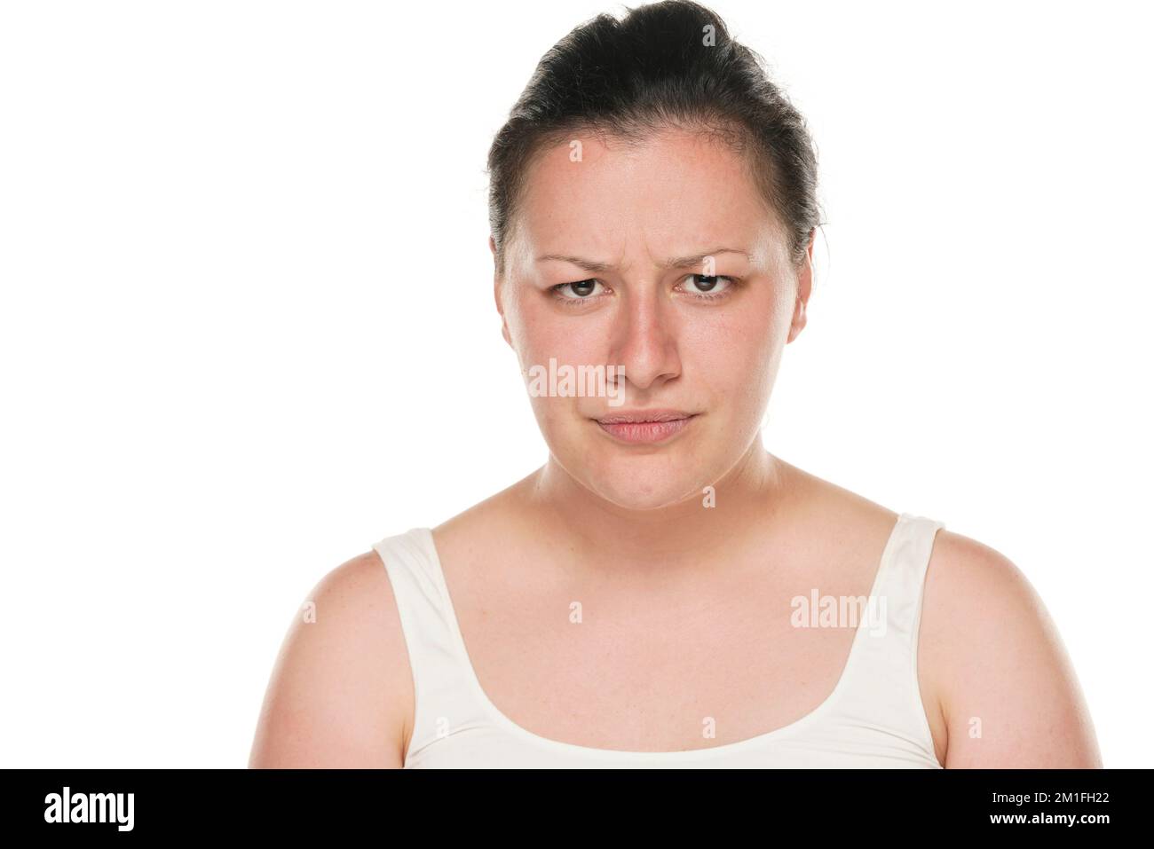 Portrait of a young frowning chubby woman without makeup on a white ...