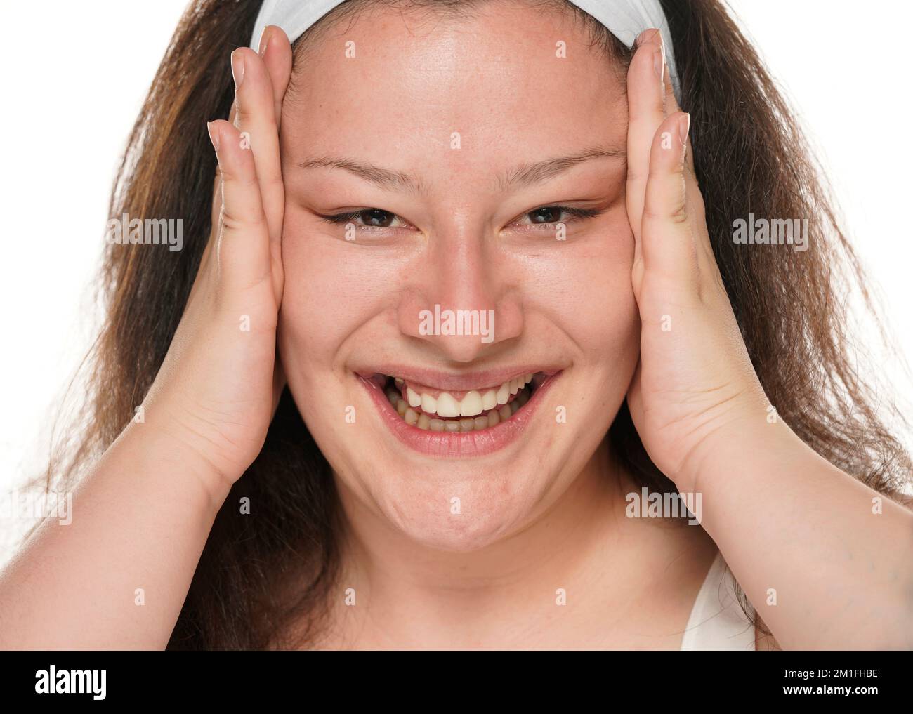 Young happy chubby woman tightening her face skin with her palms on a ...