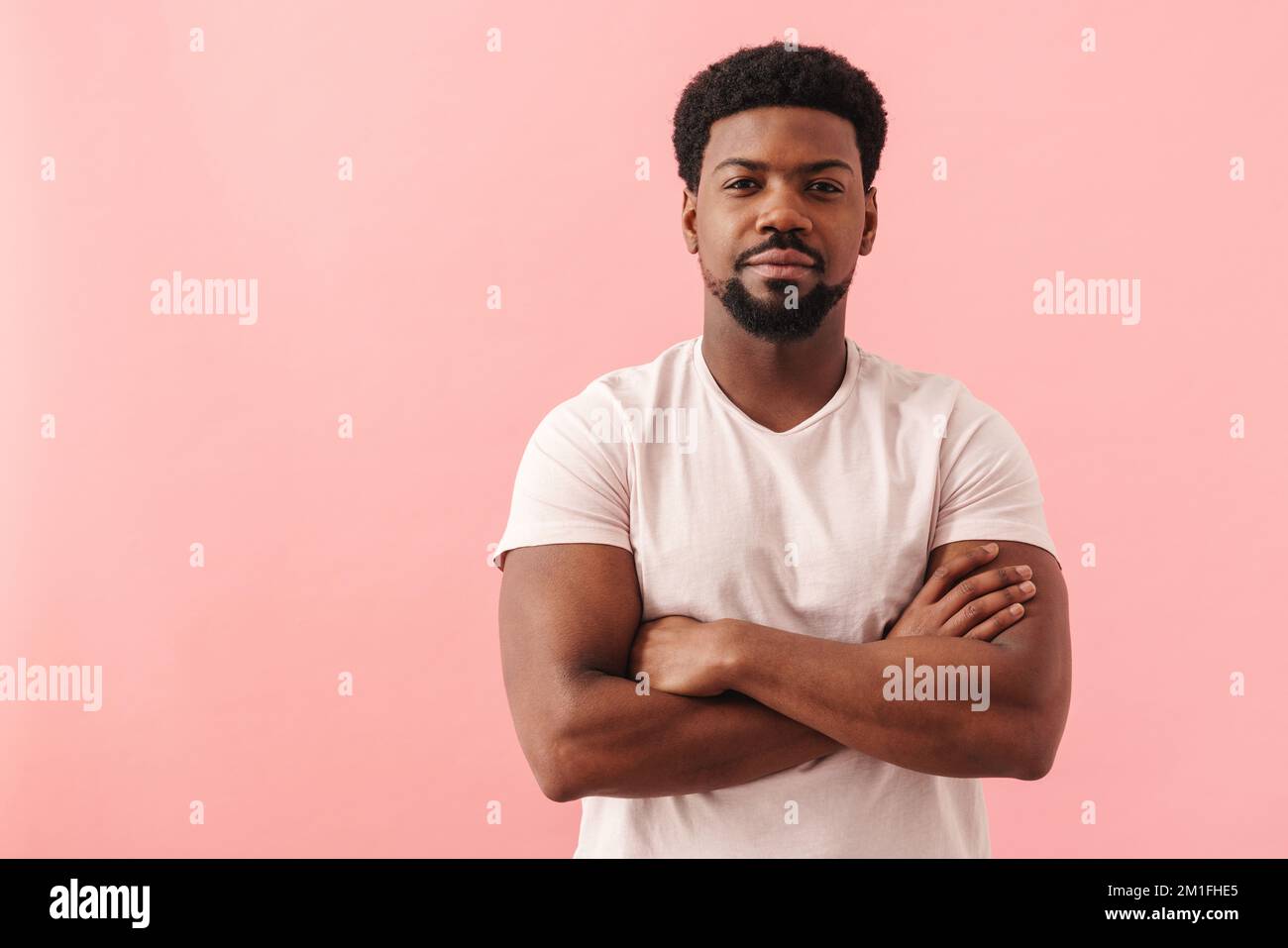 Black mid man looking at camera while posing with arms crossed isolated ...
