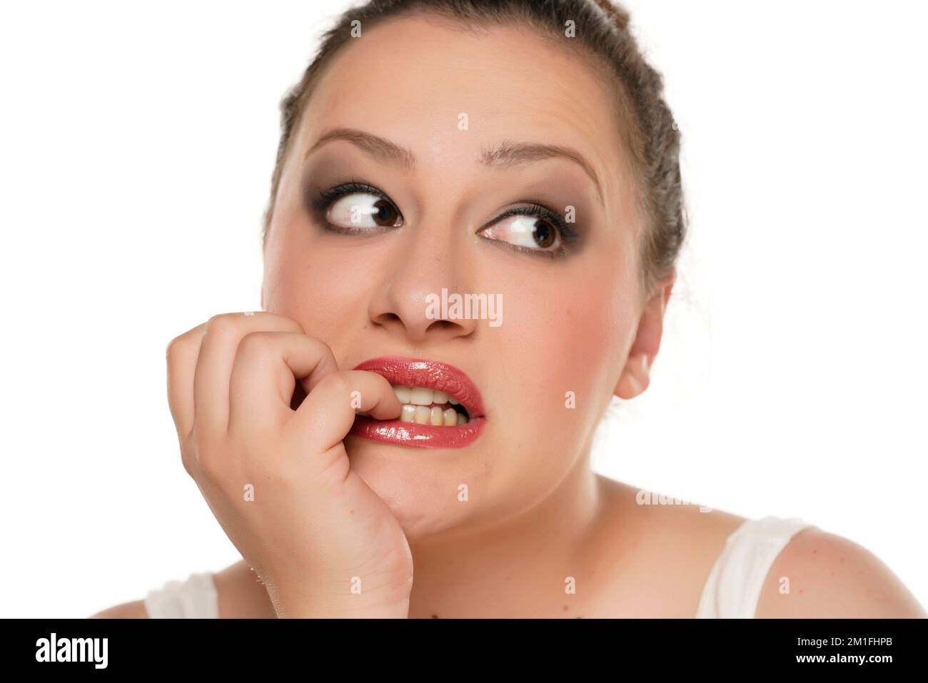 Young concerned chubby woman biting her fingernails on white studio ...