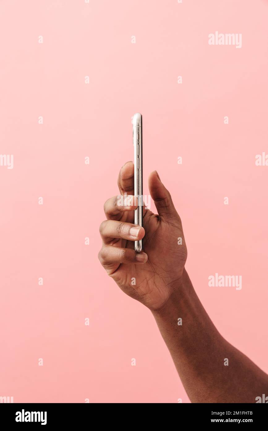 Photo of black man's hand with mobile phone isolated over pink ...