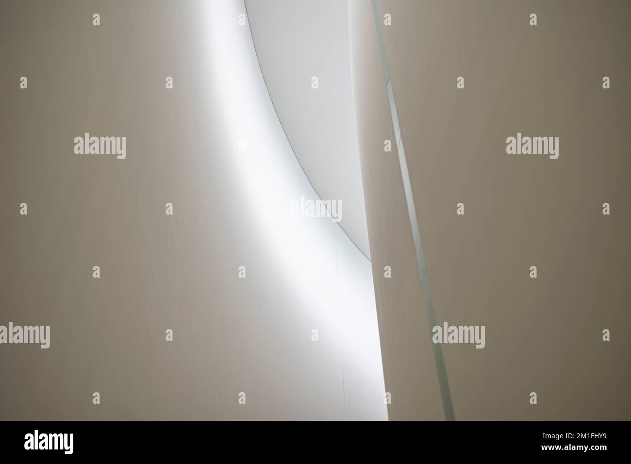 A low-angle shot of a curved modern building ceiling interior with ...