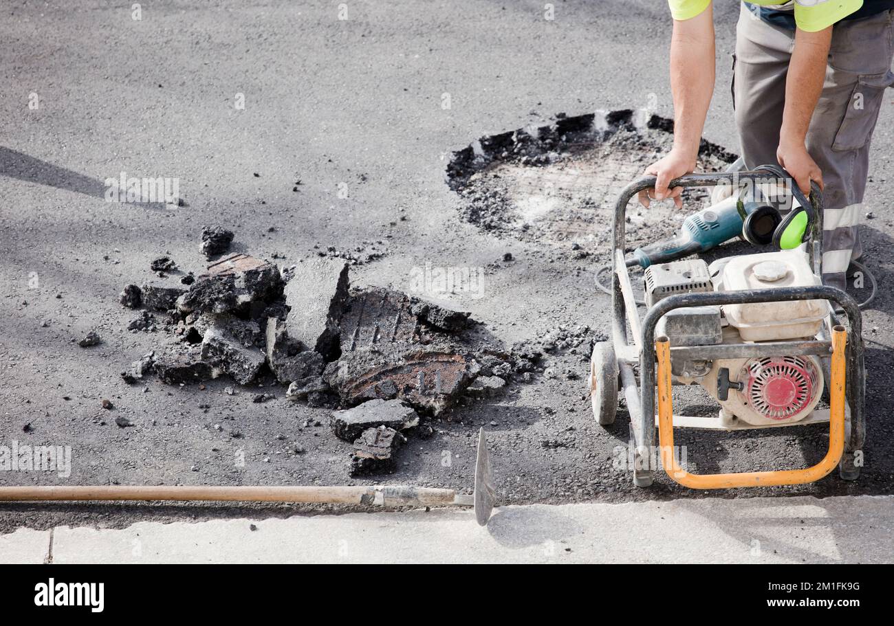 worker in uniform and electric generator machine with asphalt at ...