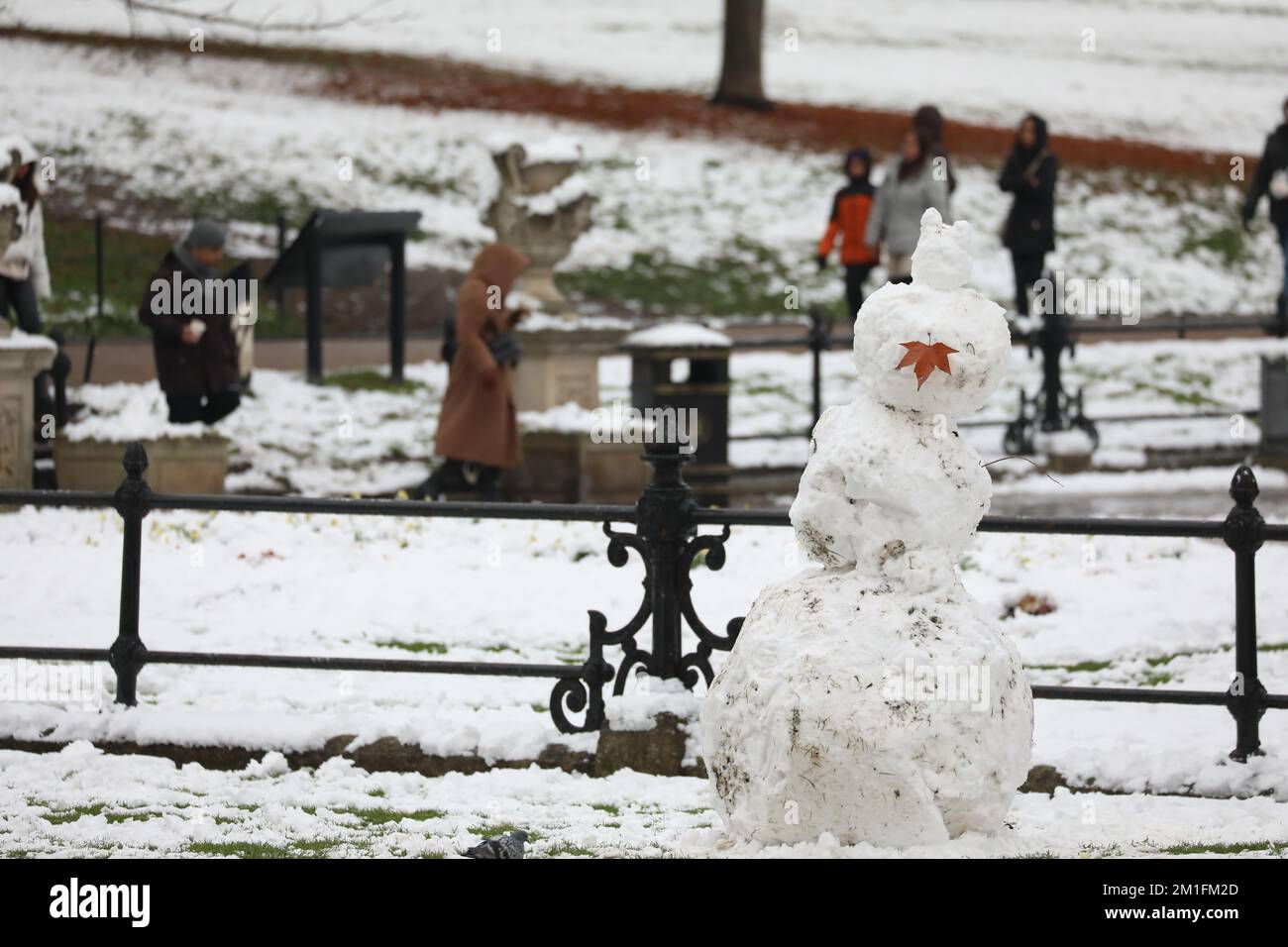 People walk by a snowman in Hyde Park, central London. Snow and ice ...