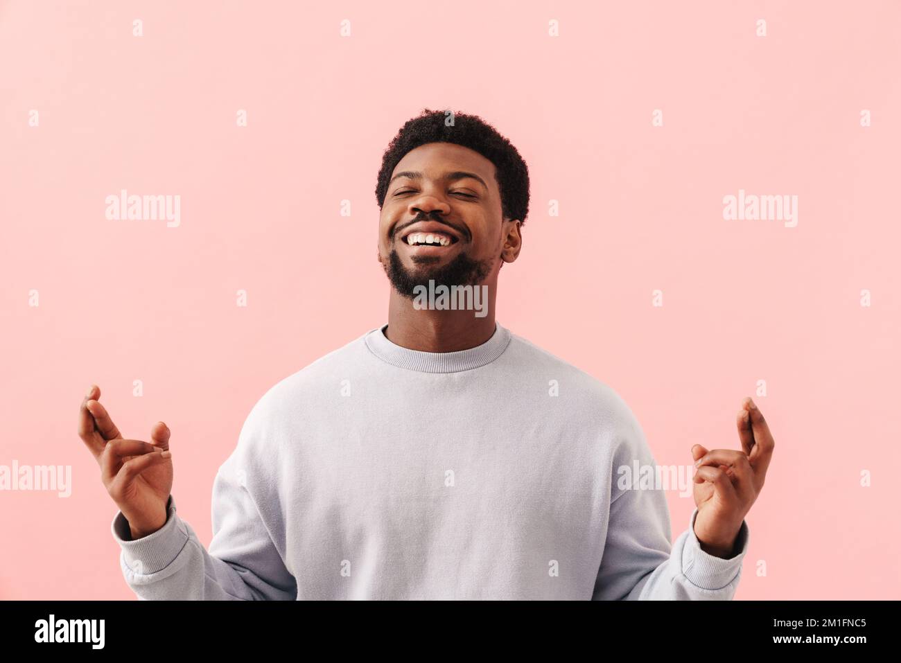 Black mid man smiling and holding fingers crossed for good luck ...