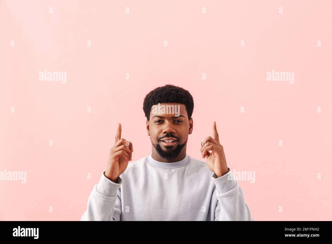 Black mid man with beard smiling and pointing fingers upward isolated ...