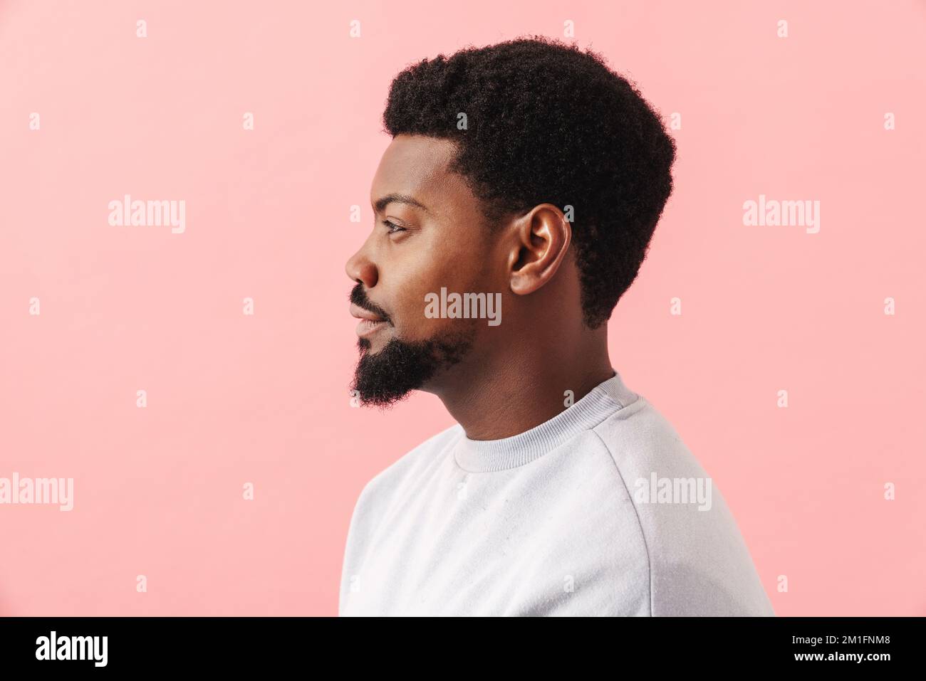 Black mid man with beard looking aside while posing in profile isolated ...