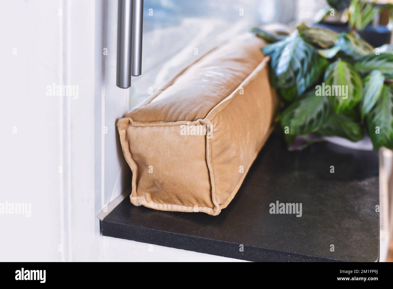 Draft excluder lying on window still to keep out cold air and save ...