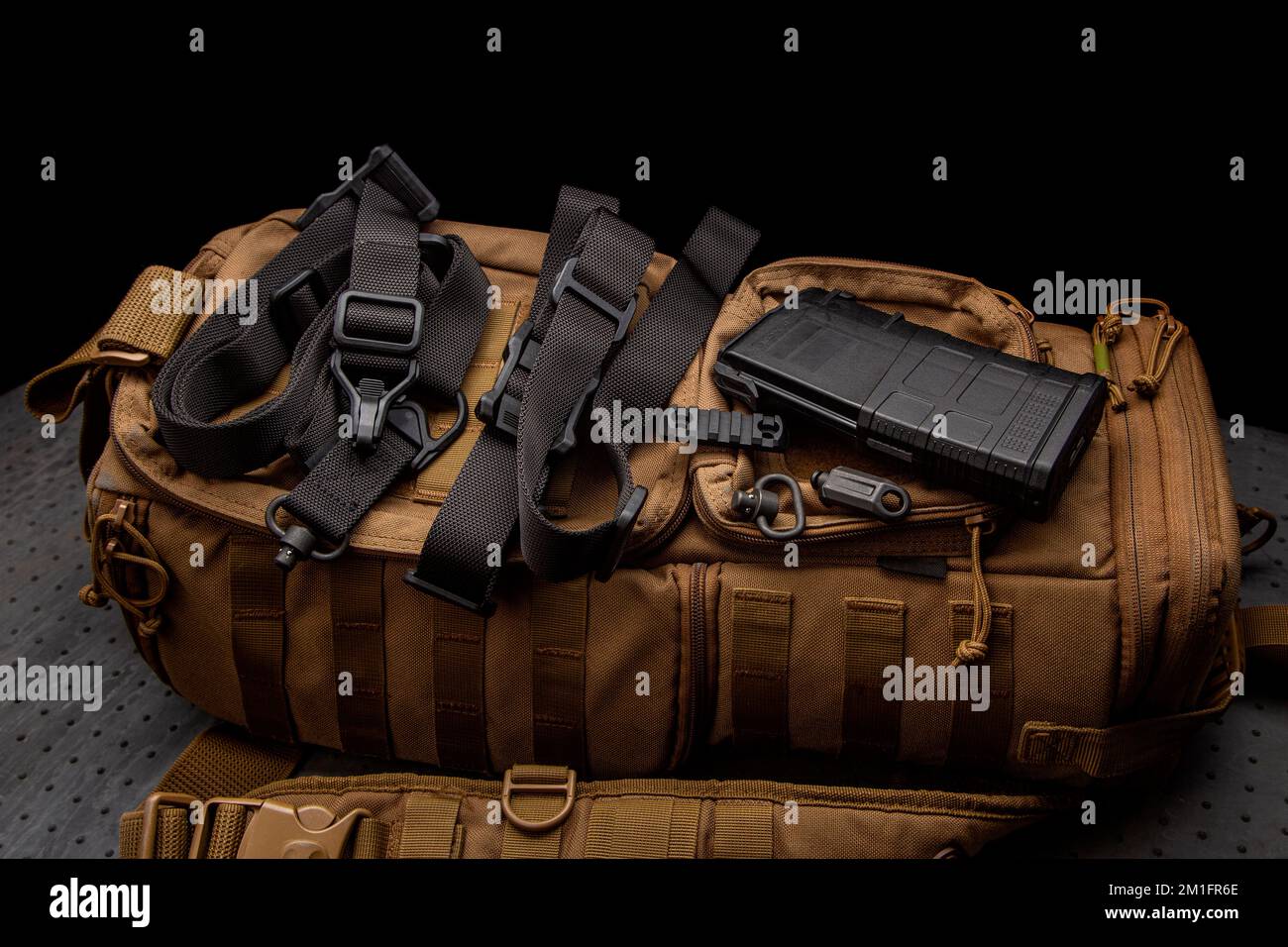 A black nylon weapon belt on a brown military backpack. Dark background ...