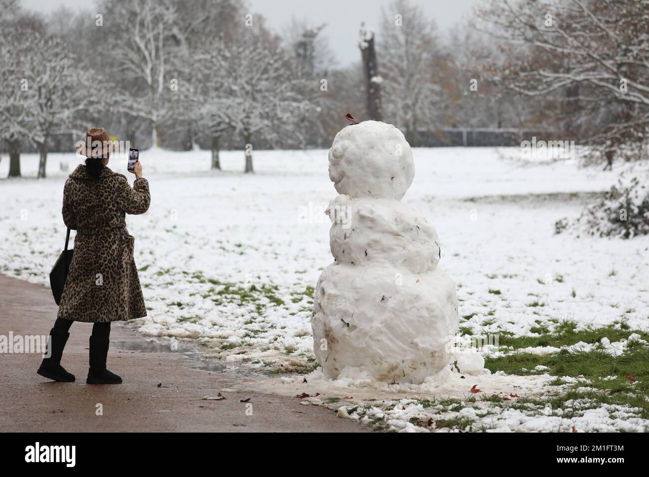 A woman takes a photograph of a snowman in Hyde Park, central London ...