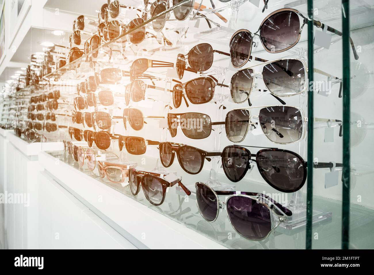 Sunglasses on display shelves in glasses store Stock Photo - Alamy