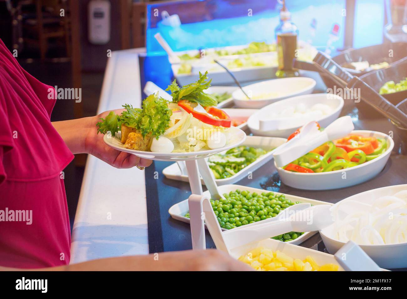 Asian woman choosing vegetable ingredients at salad bar buffet ...