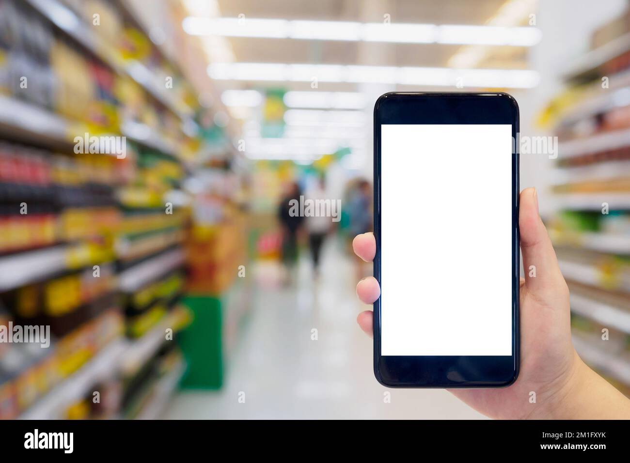 Woman hold mobile phone while shopping in supermarket Stock Photo - Alamy
