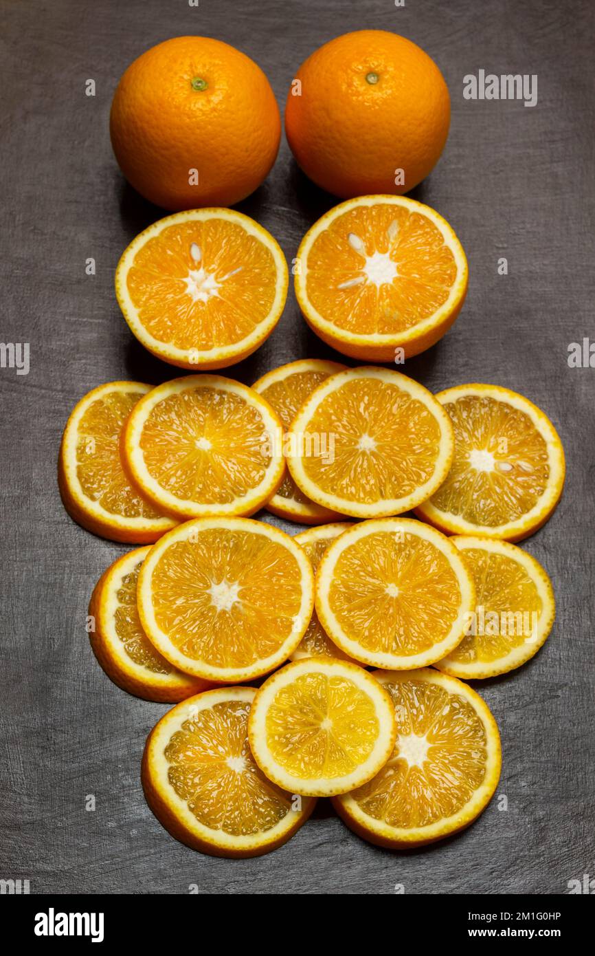 Sliced oranges and two whole oranges. Brown background. Flat lay Stock ...